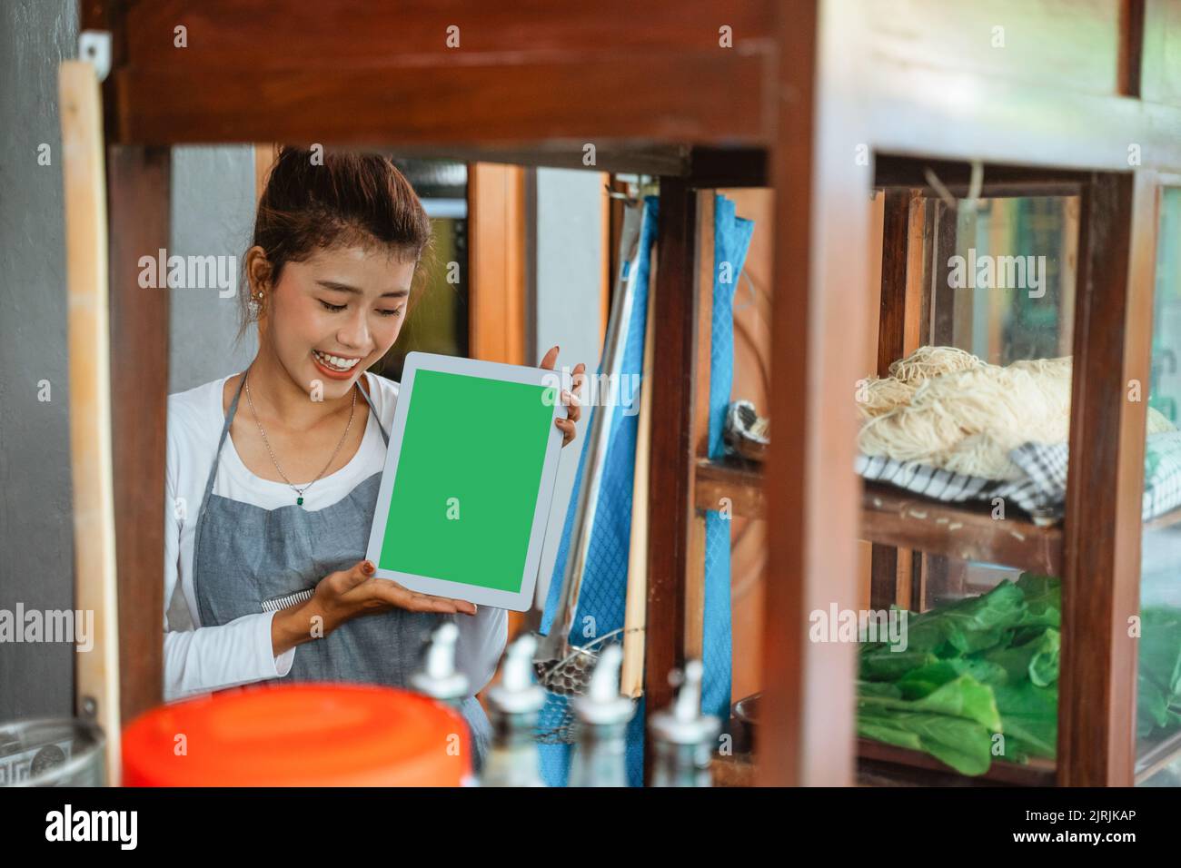 female noodle vendor in apron showing a pad screen Stock Photo - Alamy