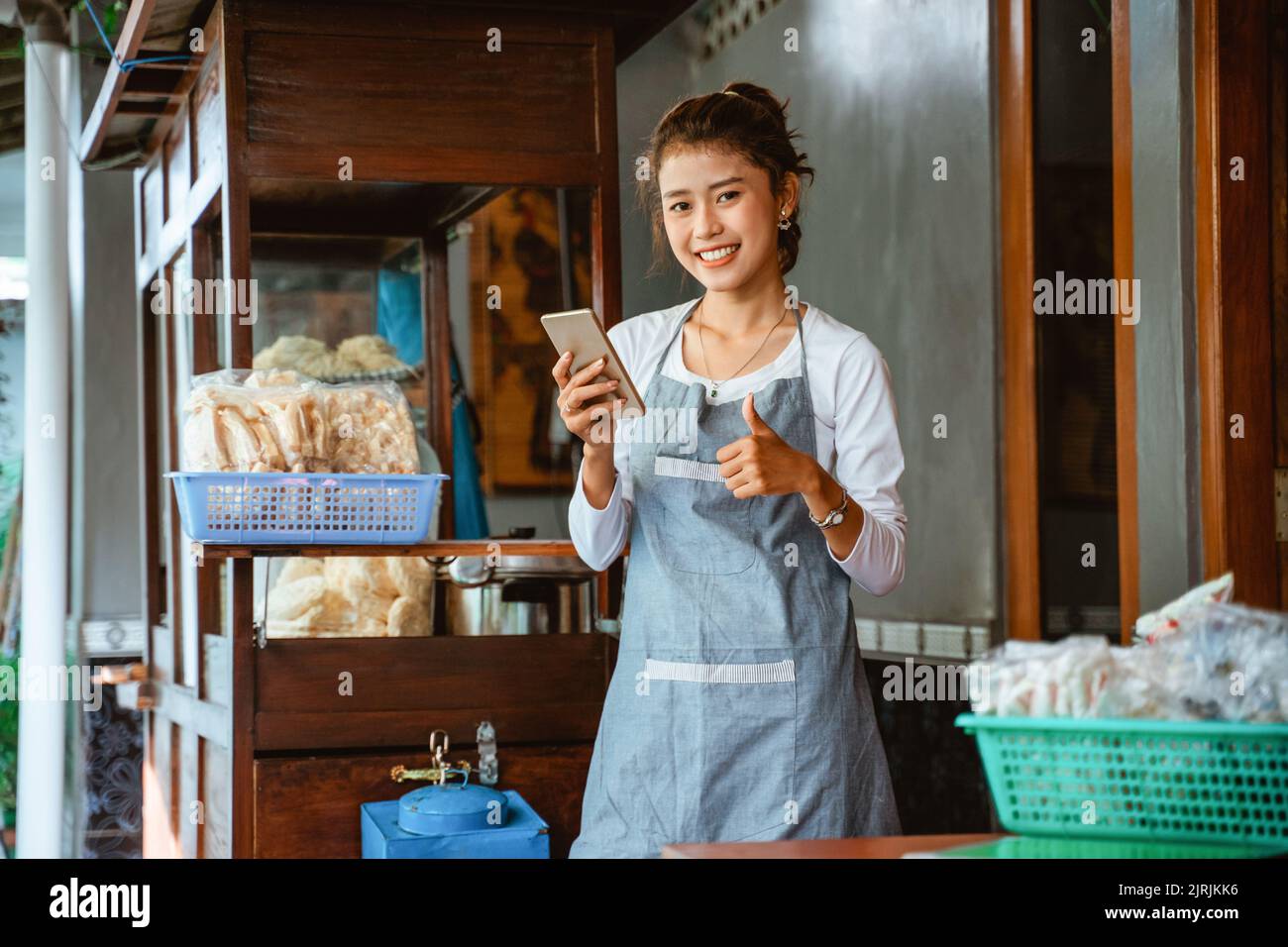 female seller smiling with thumbs up while using mobile phone Stock ...
