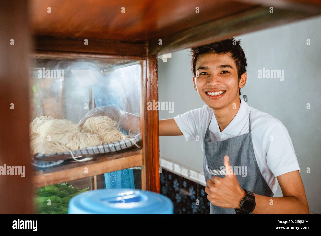 selling man smiling with thumbs up while taking noodles Stock Photo - Alamy