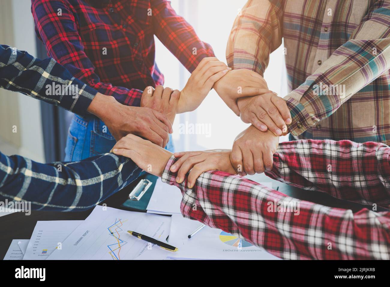 A diverse group of people connects their hands as a supportive sign ...