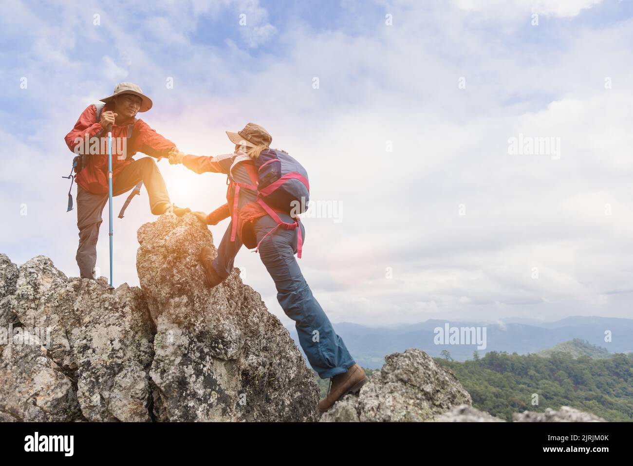 Team of climbers man and woman help each other on top of mountain ...