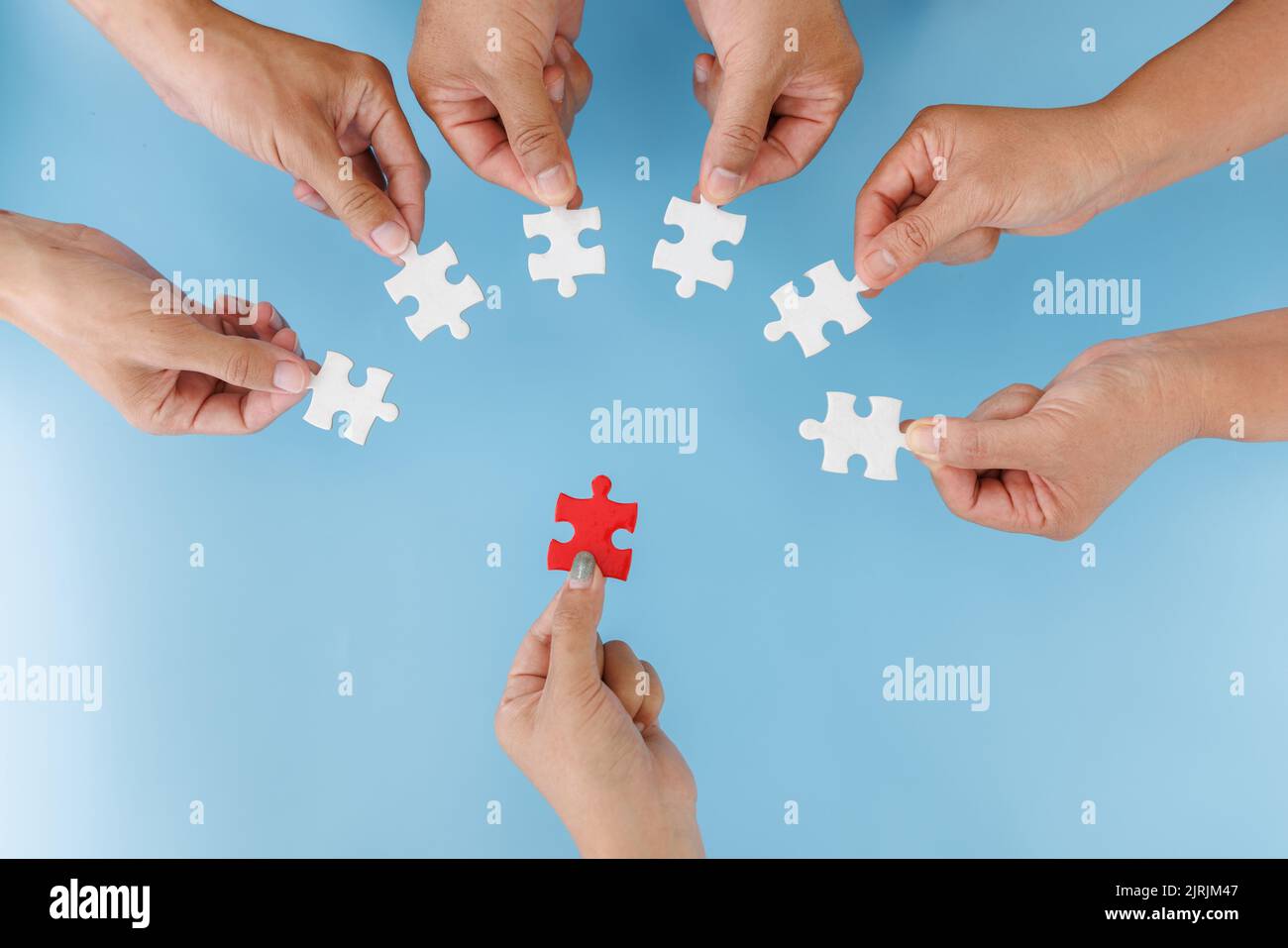 Group of business people assemble jigsaw puzzles on blue background ...