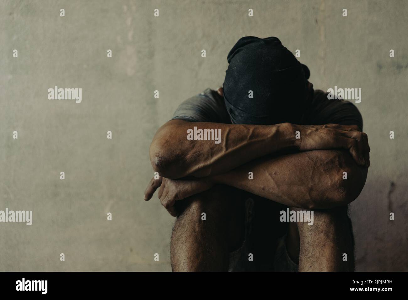 A drug addicted homeless man sitting alone and depressed in an ...