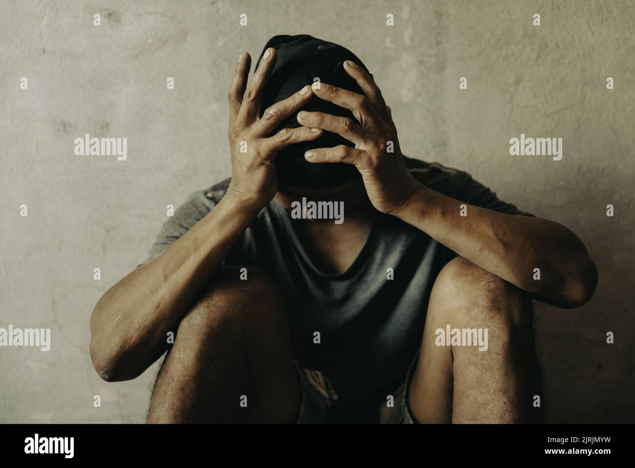 A drug addicted homeless man sitting alone and depressed in an ...