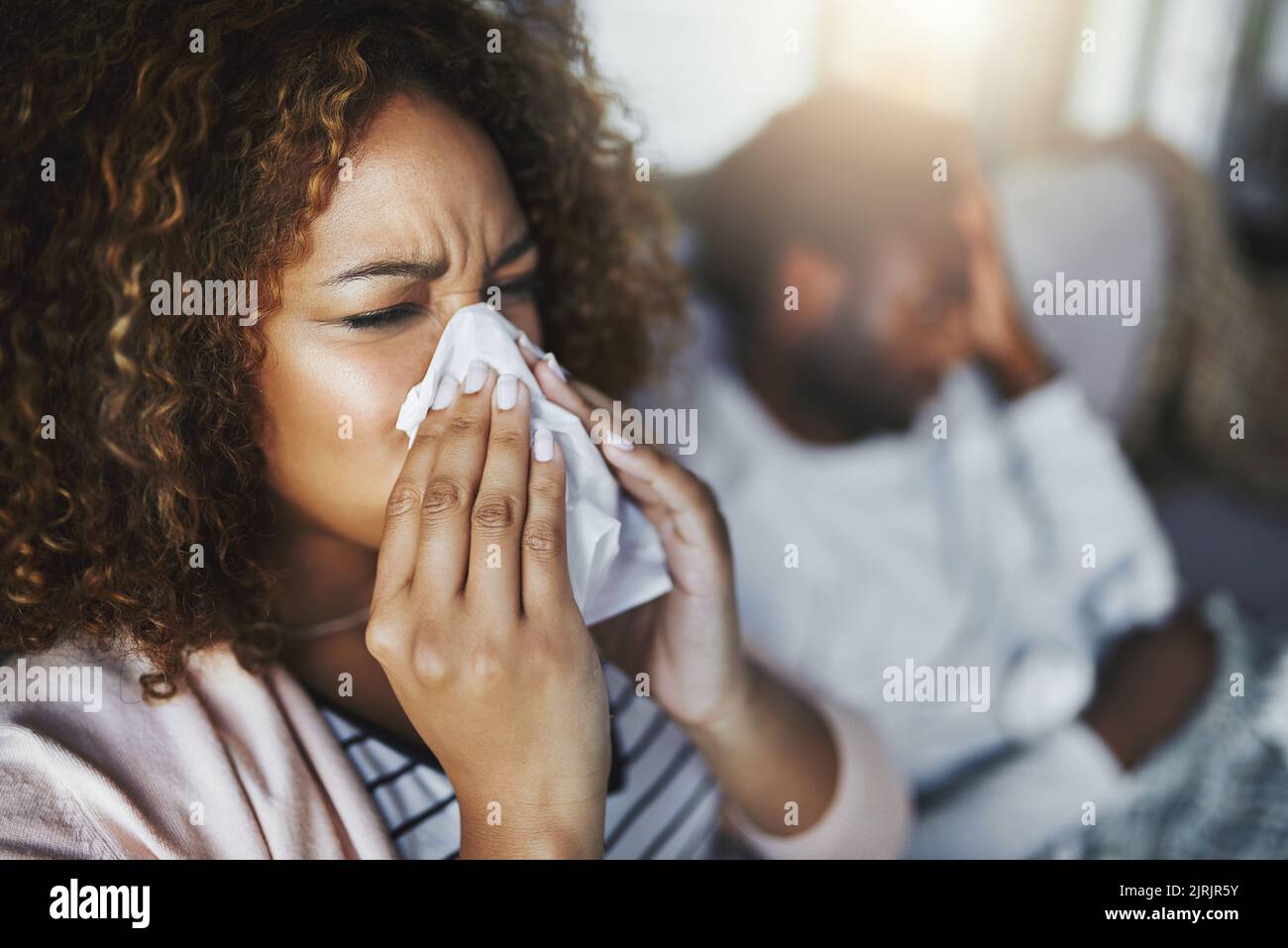 Its the height of cold and flu season. a young woman blowing her nose ...