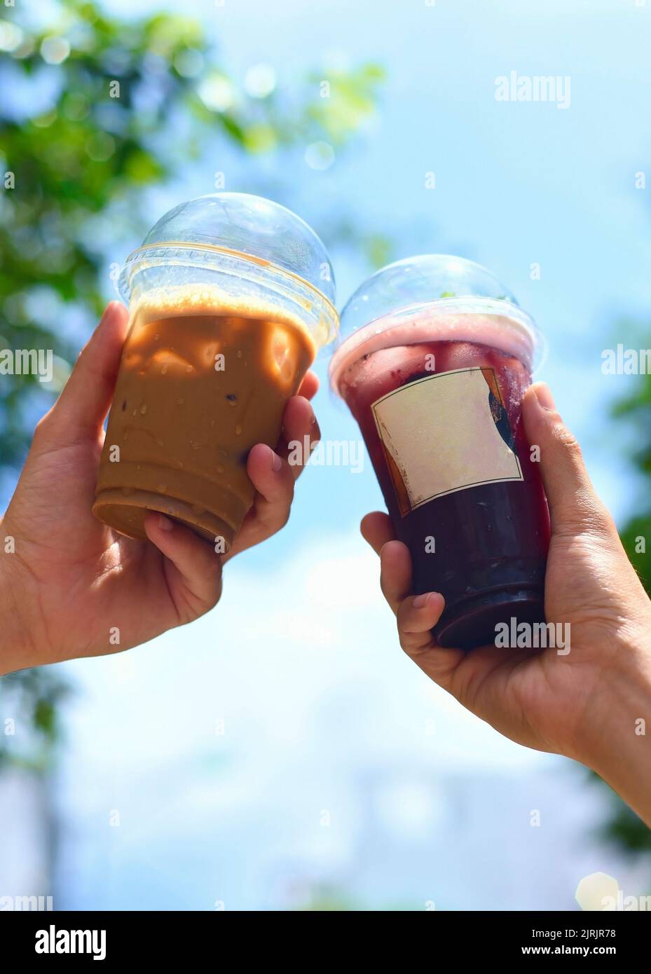 Hand clinking plastic cups of coffee and mulberry tea closeup Stock ...