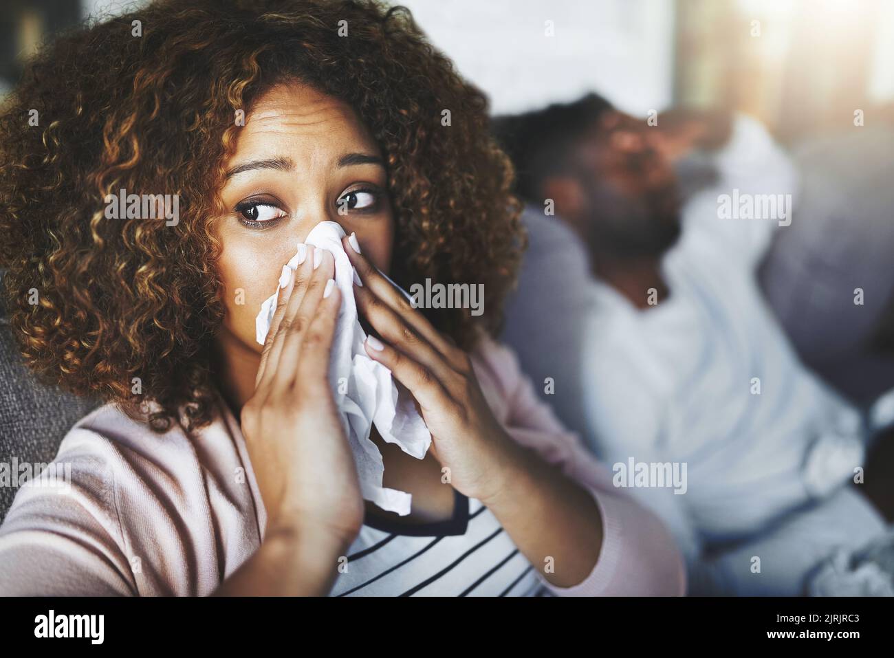Flu season is in full swing. a young woman blowing her nose while ...