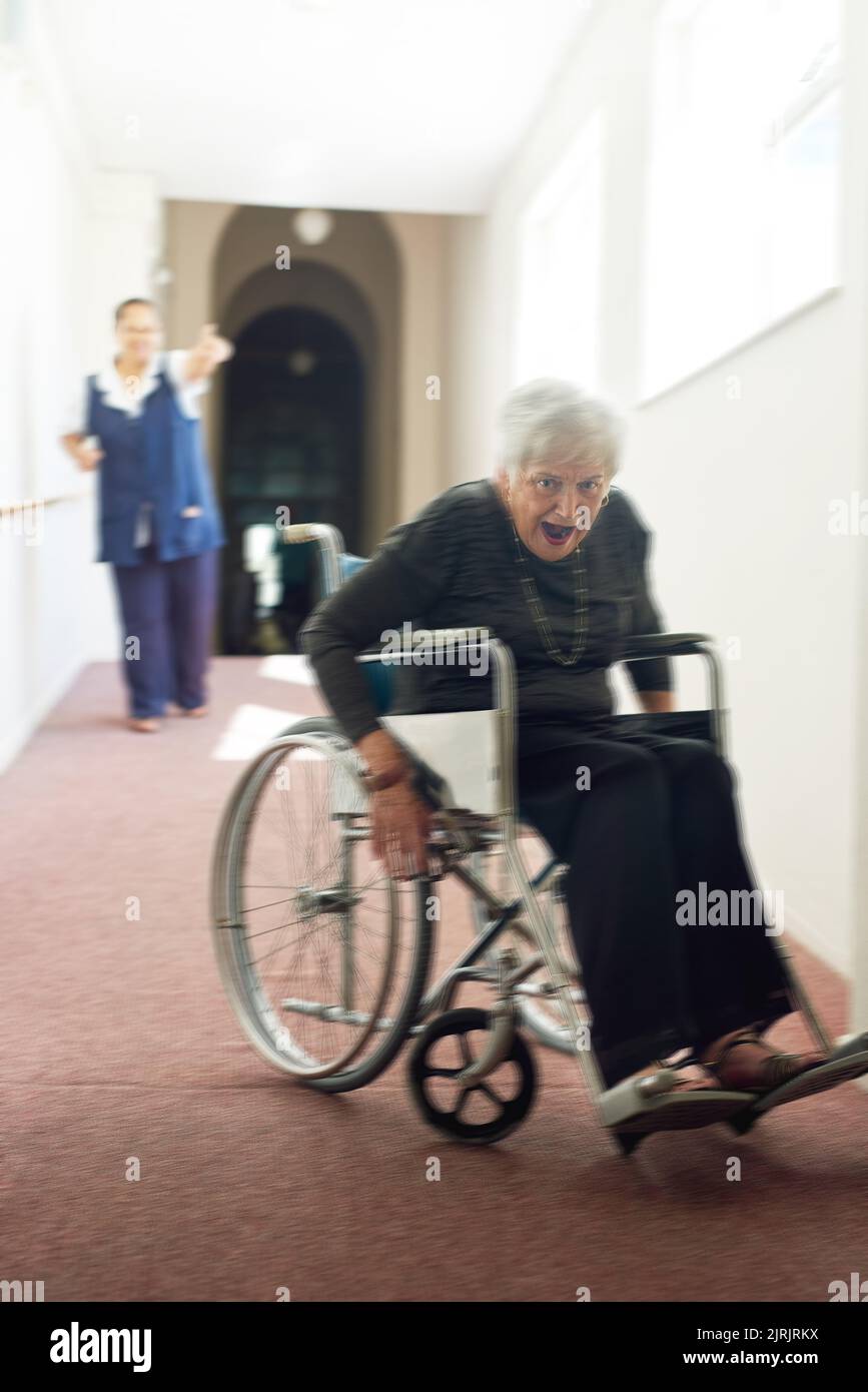 Catch me if you can. a mischievous senior woman using her wheelchair to ...