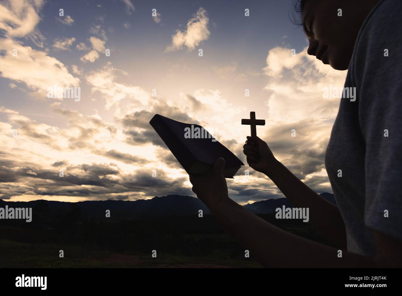 Silhouette of woman praying with cross in nature sunrise background ...
