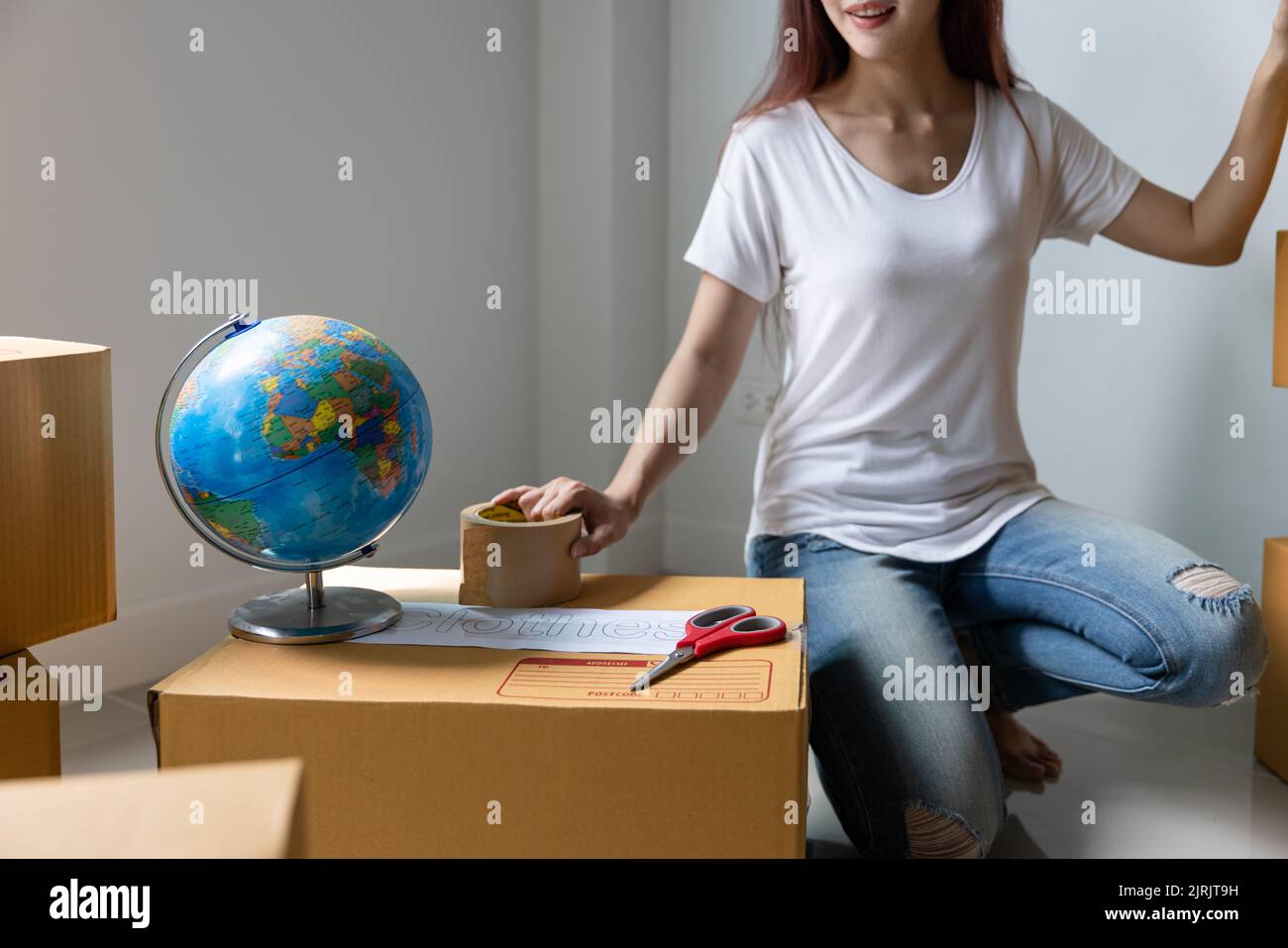 An Asian woman checks items before packing them in cardboard to move ...