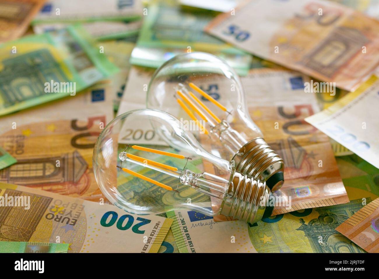 Electricity cost.Two light bulbs on euro bills.Rising electricity ...