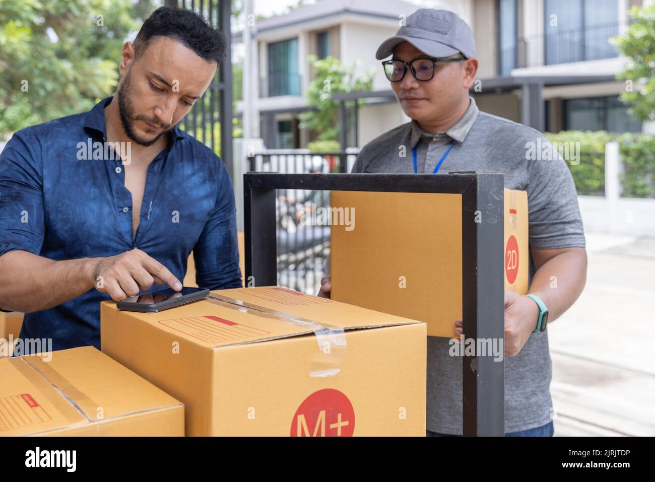 Two Young Delivery Man Carrying Cardboard Box and check the items in ...