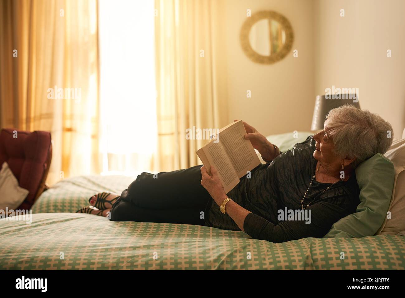 Keeping her mind active and engaged. a relaxed senior woman reading a ...