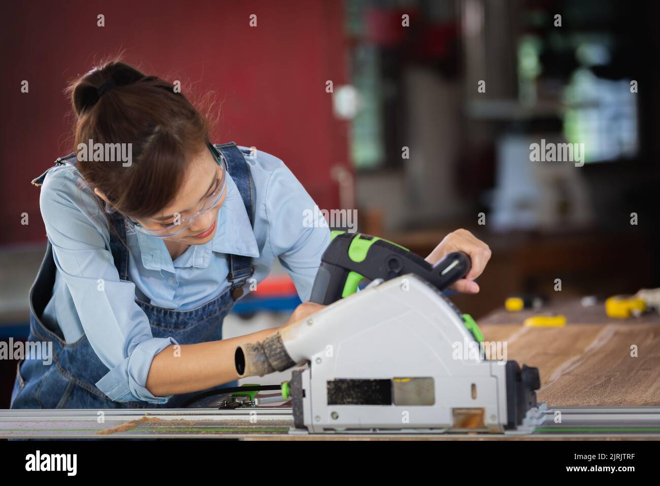 woman works in a carpentry shop. Attractive female carpenter using some ...