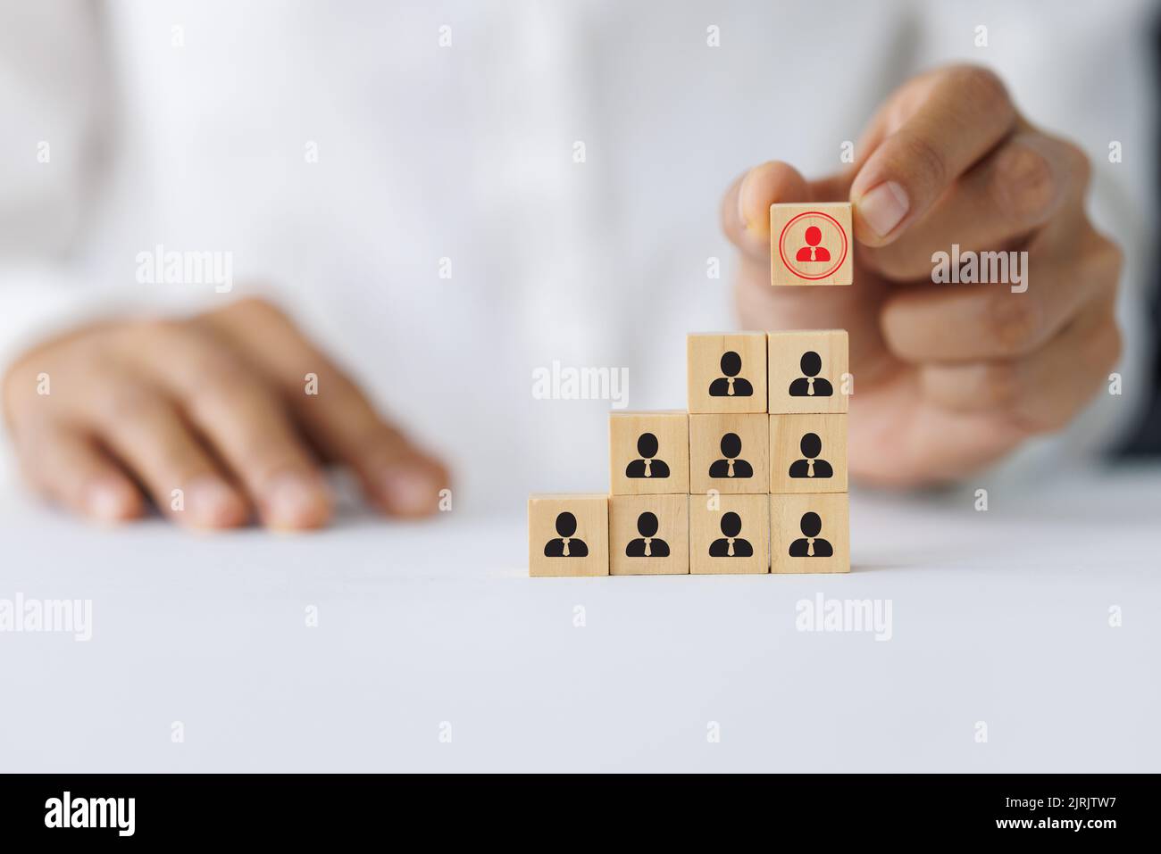 Hand holding a wooden block with people icon above mint square ...