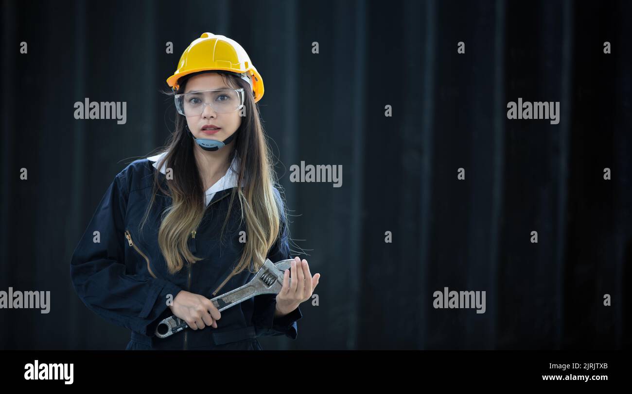 Portrait of a beautiful Asian engineer holding a wrench The background ...