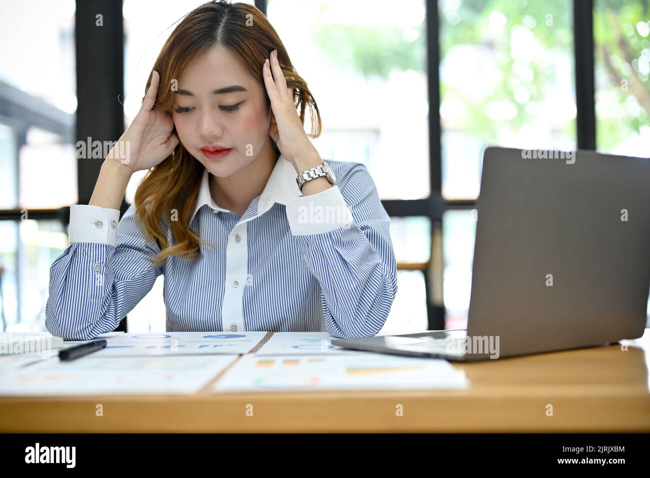 Stressed young Asian businesswoman or female office worker working on ...