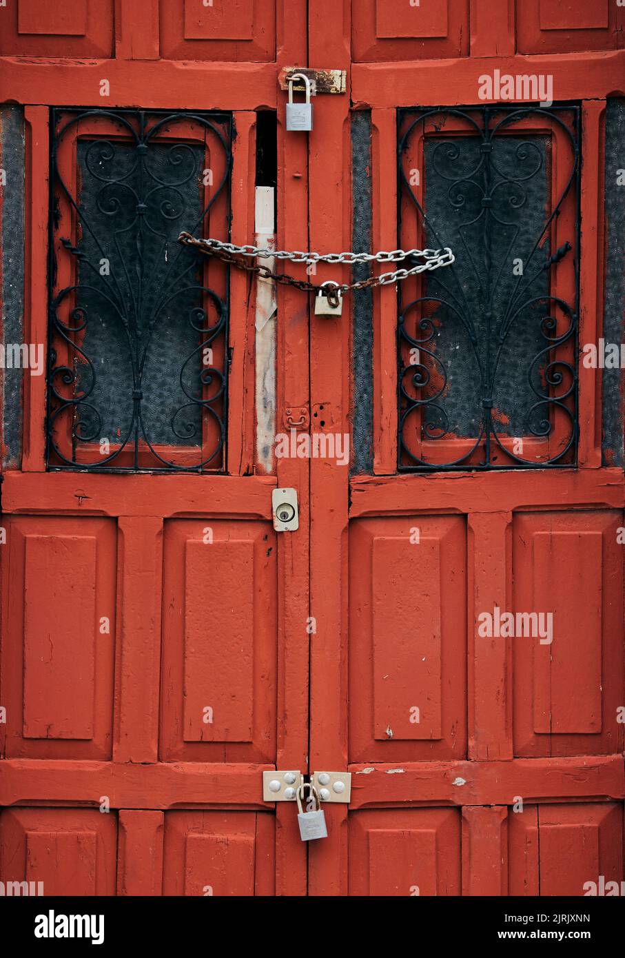 An old red door locked up with several locks Stock Photo - Alamy