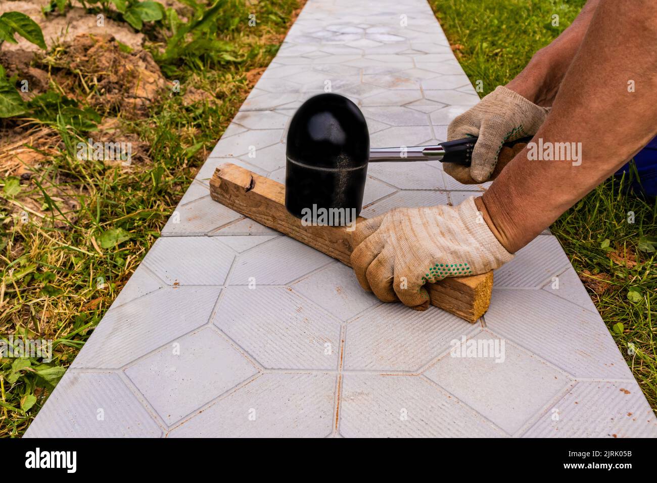 the hands of a professional worker hit the slab with a special rubber ...