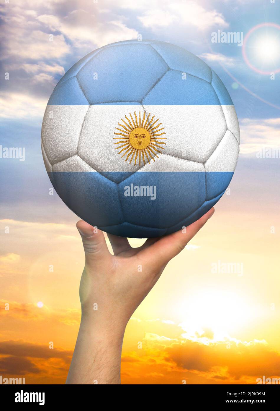 Soccer ball in hand with a depiction of the flag of Argentina against a ...
