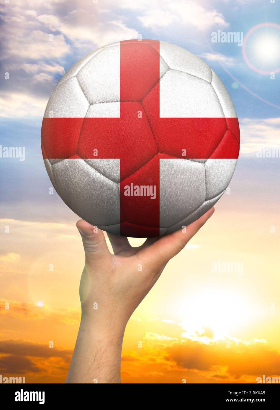 Soccer ball in hand with a depiction of the flag of England against a ...