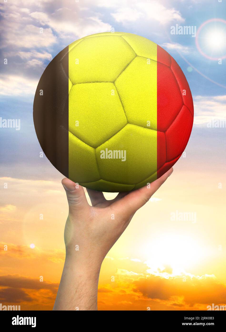 Soccer ball in hand with a depiction of the flag of Belgium against a ...