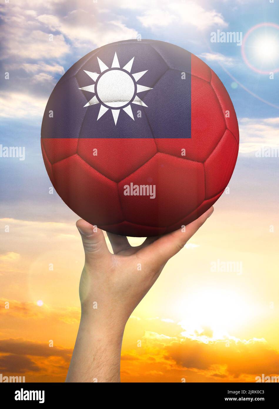 Soccer ball in hand with a depiction of the flag of Taiwan against a ...