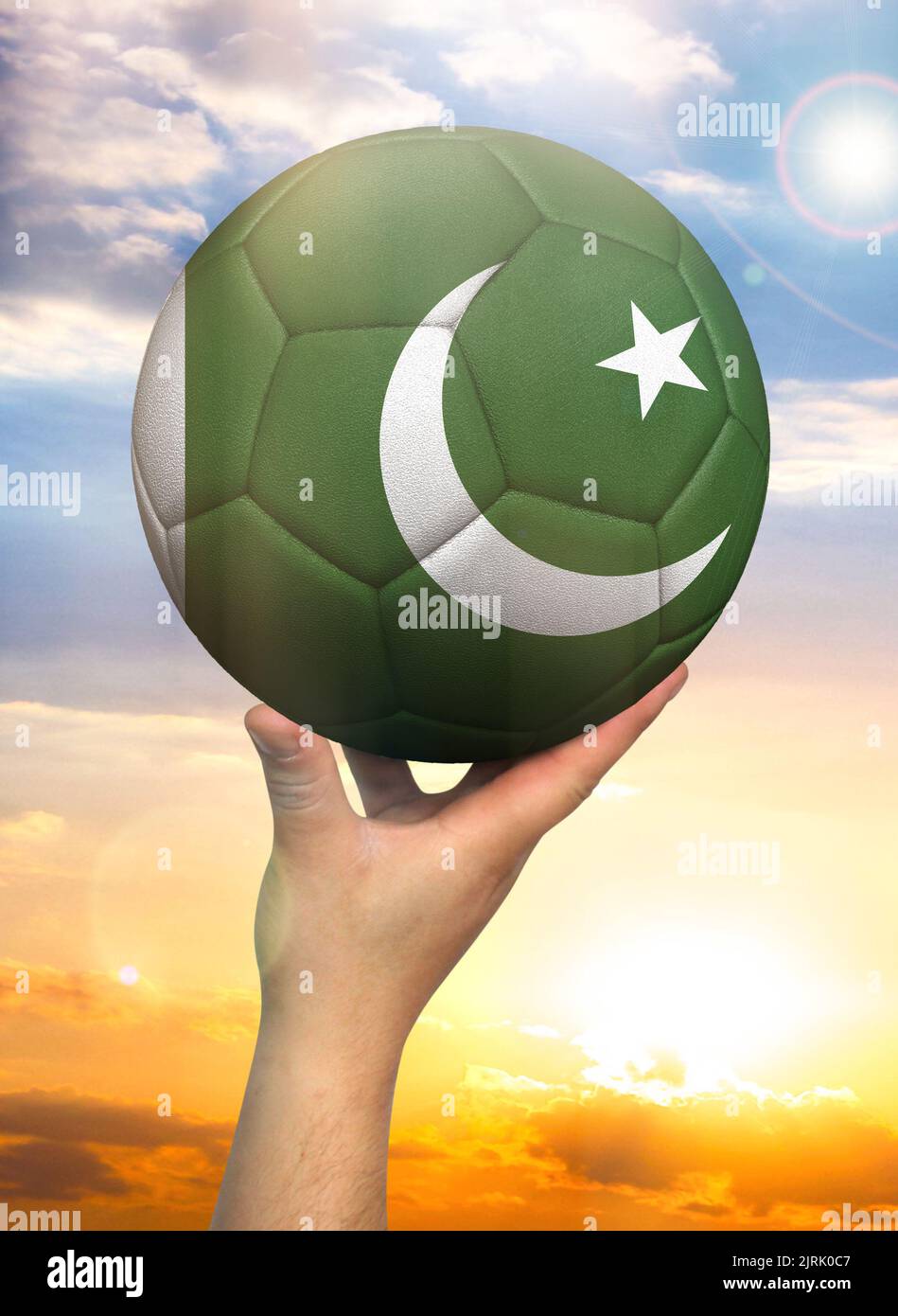 Soccer ball in hand with a depiction of the flag of Pakistan against a ...