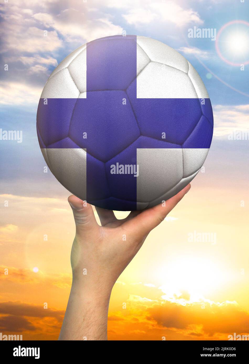 Soccer ball in hand with a depiction of the flag of Finland against a ...