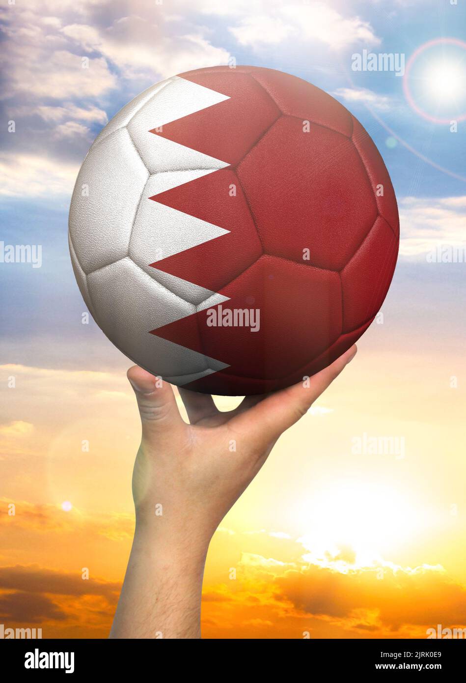 Soccer ball in hand with a depiction of the flag of Bahrain against a ...