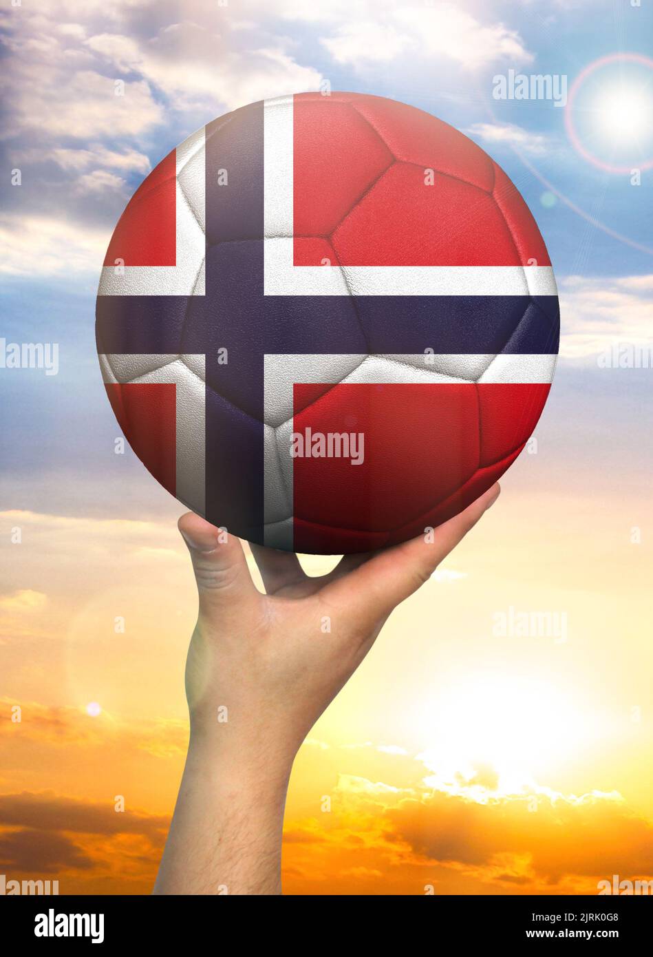 Soccer ball in hand with a depiction of the flag of Norway against a ...