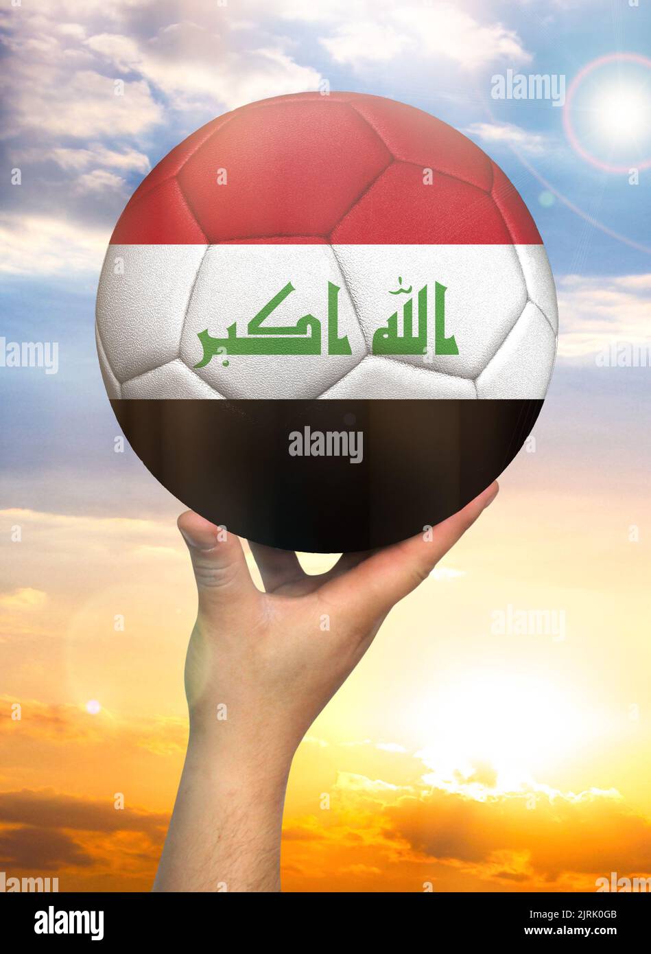 Soccer ball in hand with a depiction of the flag of Iraq against a ...