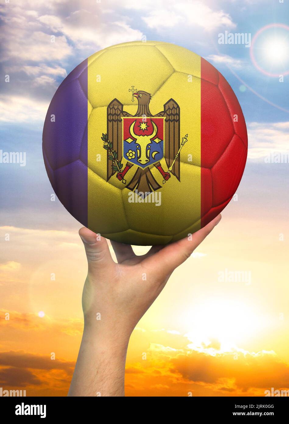 Soccer ball in hand with a depiction of the flag of Moldova against a ...