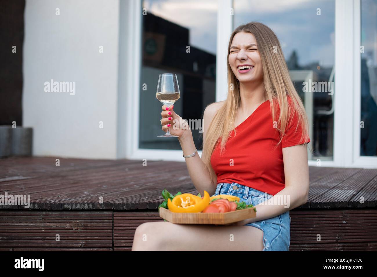 Portrait of young laughing pretty woman sitting on step of wooden ...