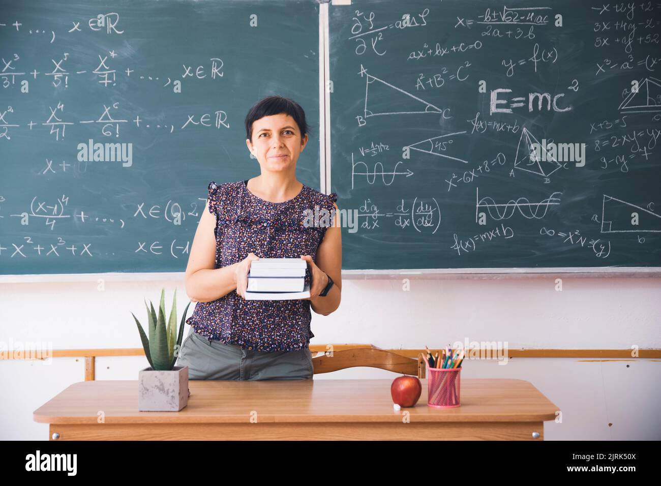 Back to school concept: teacher giving books to her studens in the ...