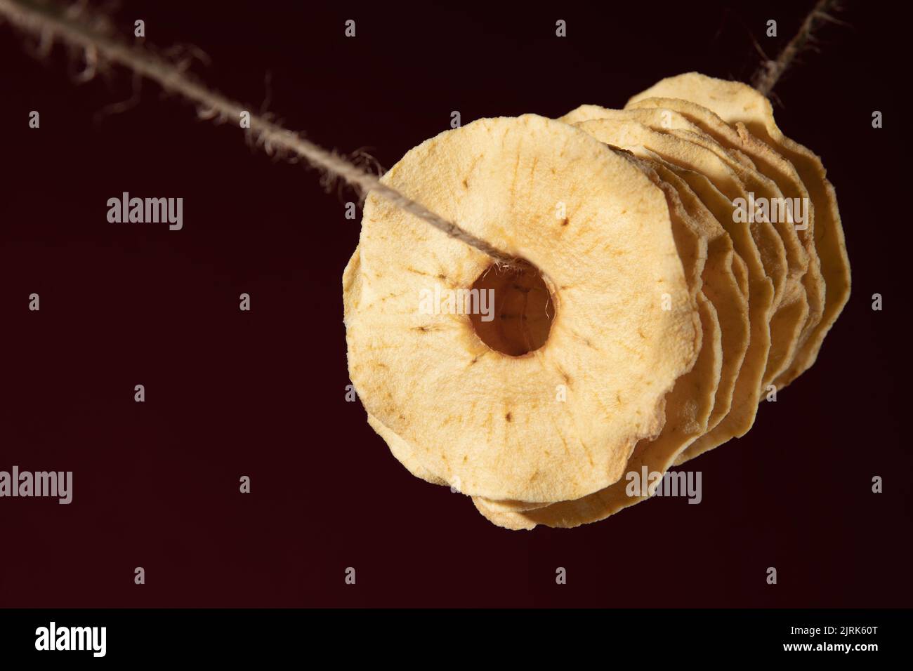 Horizontal photo. Dried apple slices on a rope on a dark background ...