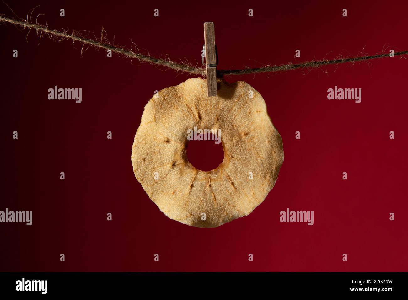 Dried apple slice on a rope on a clothespin. Dark background with empty ...