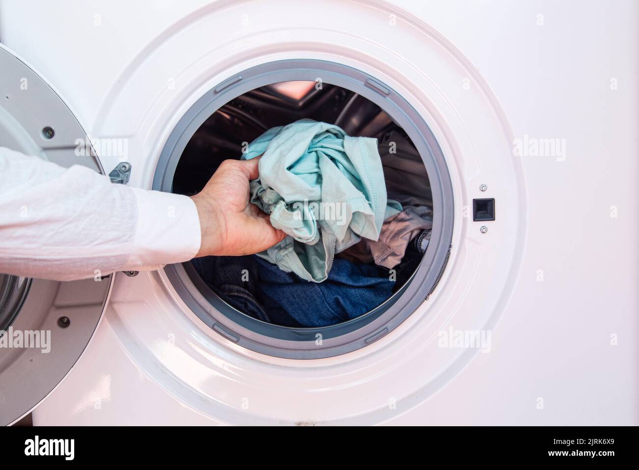 Close up of a washing machine with clothes isolated on white background ...