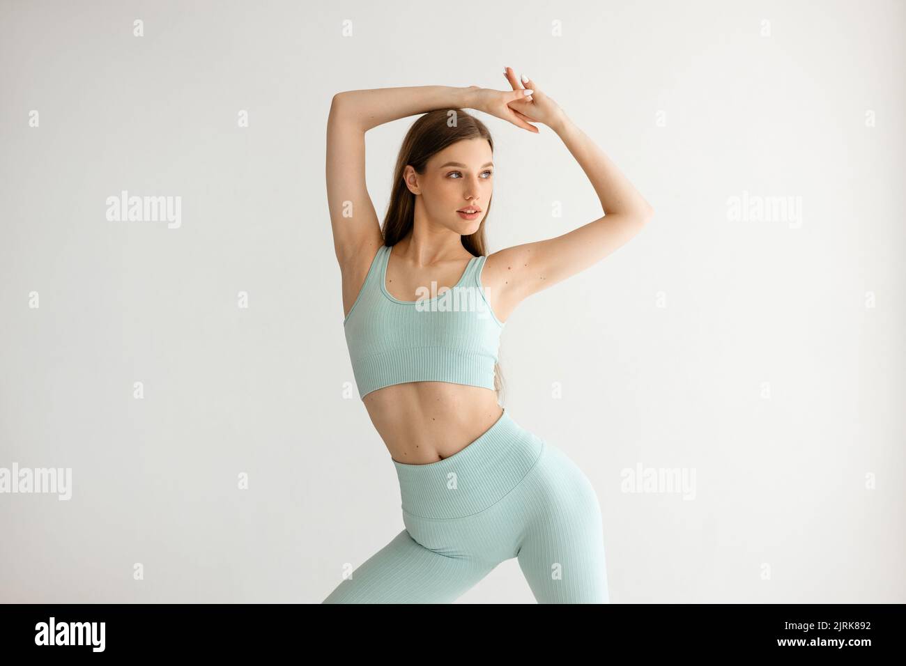 Beautiful athletic girl in a blue fitness suit on a white background ...