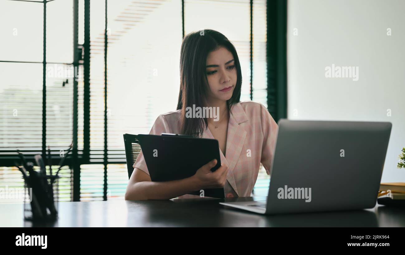 Concentrated female manager using laptop, preparing reports for ... Concentrated female manager using laptop, preparing reports for ...