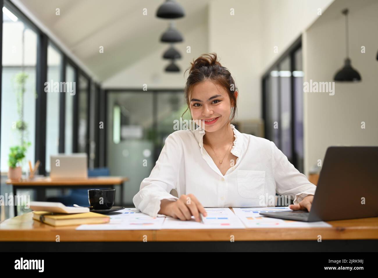 Charming young woman office worker sitting front of laptop at her ...