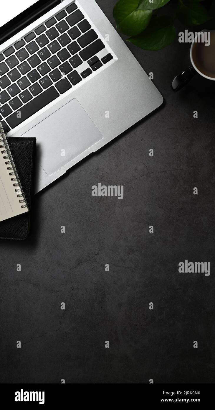 Flat lay laptop computer, notepads and coffee cup on black stone ...