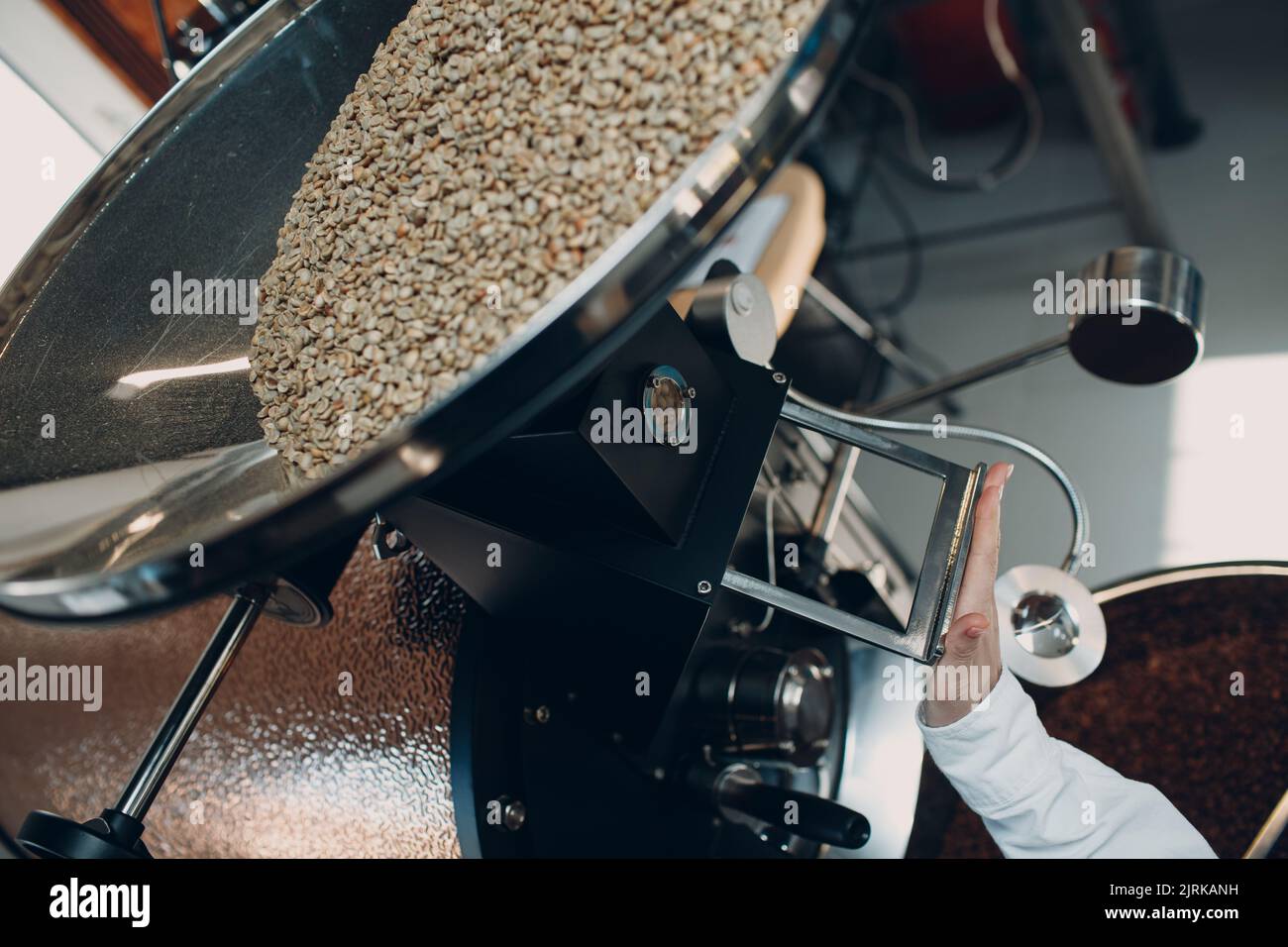 Coffee roaster machine at coffee roasting process. Young woman worker ...