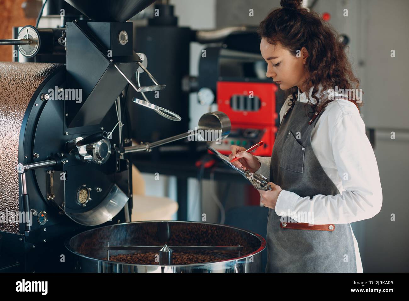 Coffee roaster machine and barista woman with tablet write pen at ...