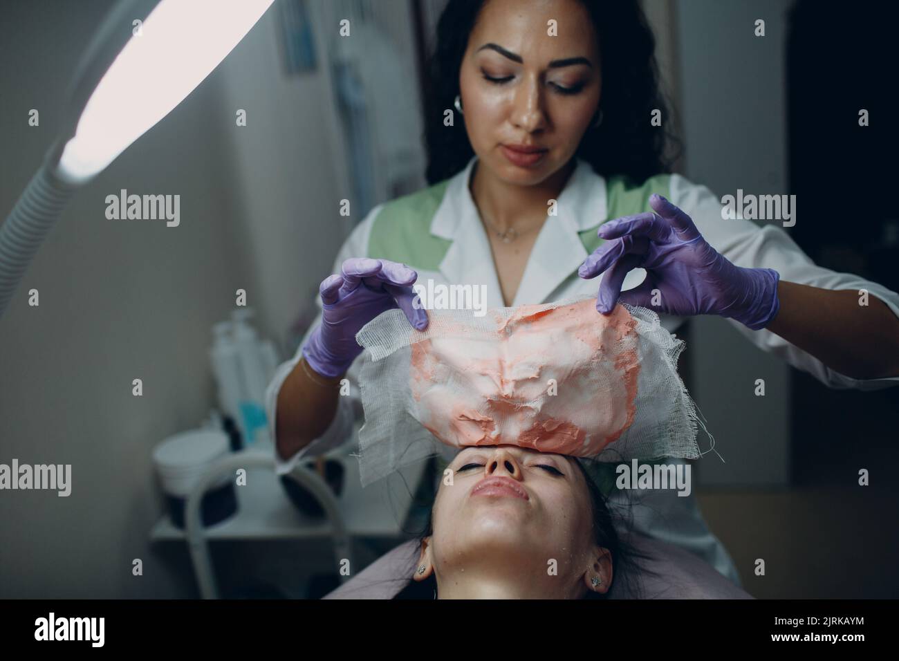 Alginate face mask application process. A female hands of a beautician ...