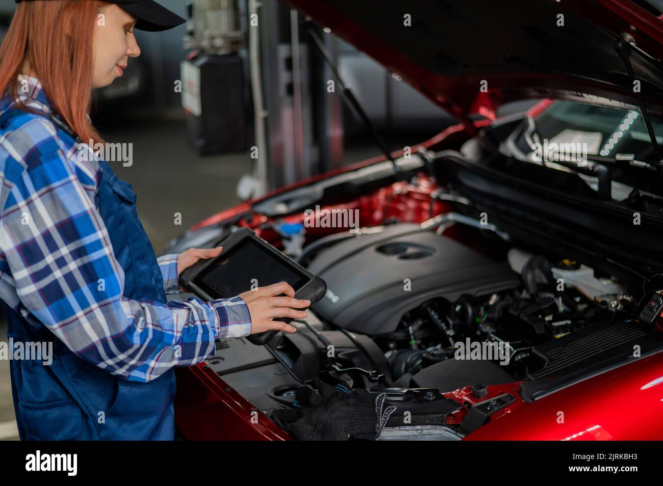 Caucasian female auto mechanic uses a special computer to diagnose ...