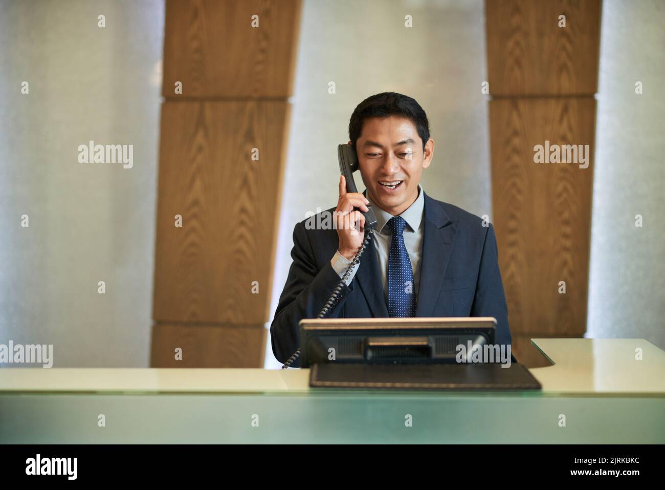 Portrait of smiling Vietnamese receptionist calling on the phone Stock ...