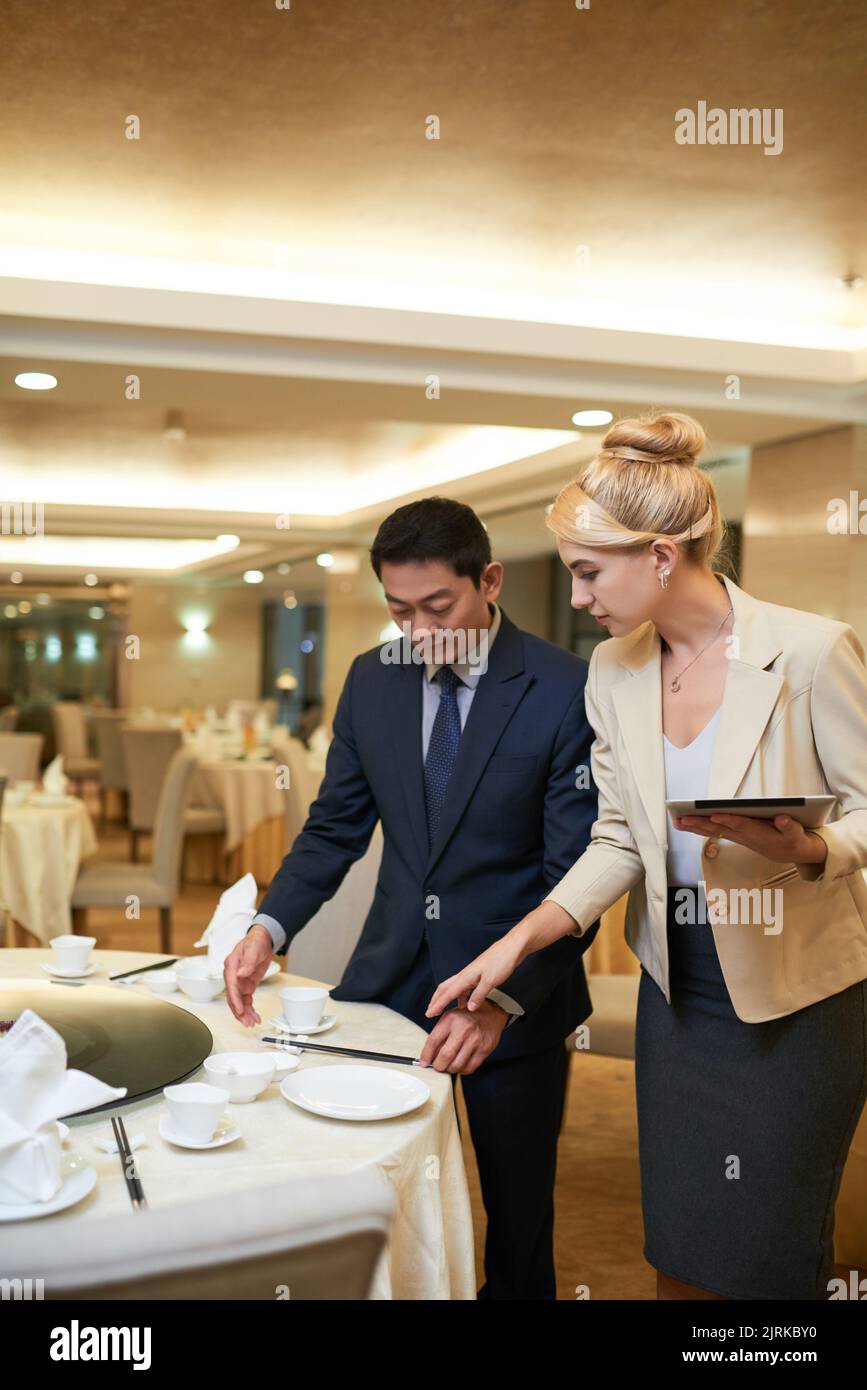 Banquet manager explaining waiter how to set the tables Stock Photo - Alamy