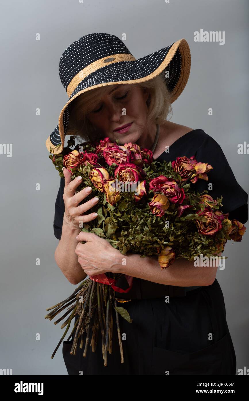 Upset elderly woman hold withered dry old rose flowers bouquet Stock ...