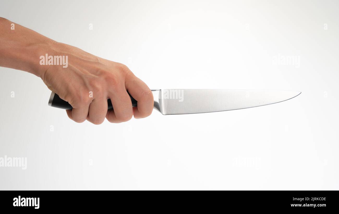 Kitchen knife in the right hand of a woman on a white background. High ...